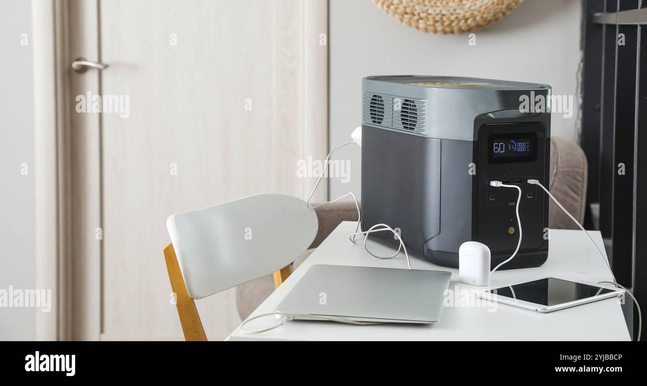 Portable power station charging devices on table in office Stock Photo ...