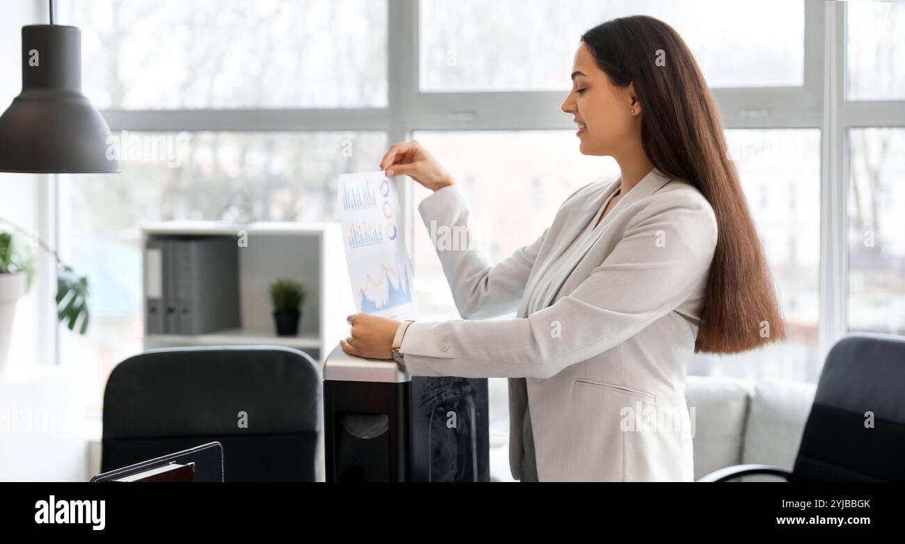 Young secretary destroying documents by using shredder in office Stock ...