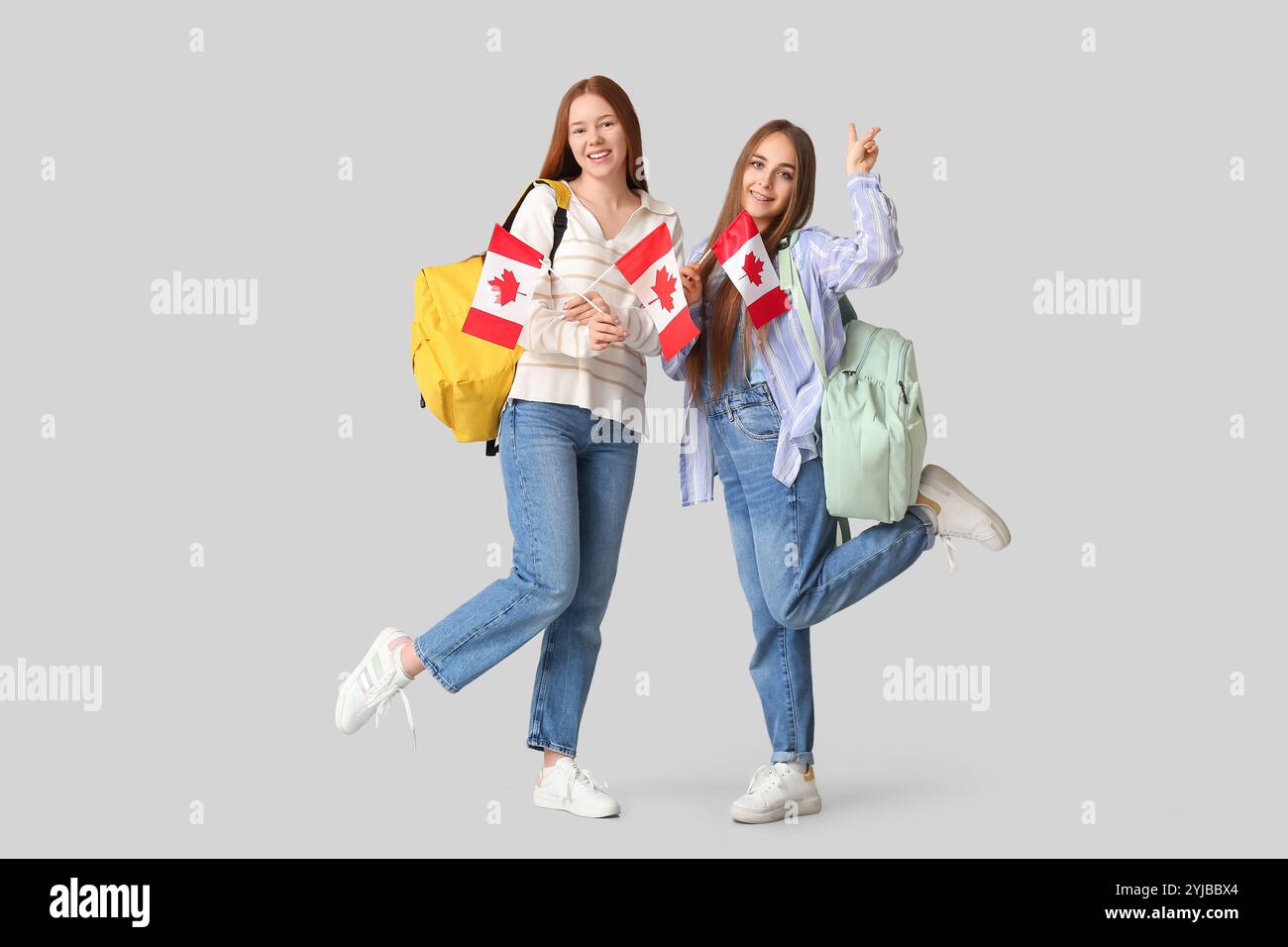 Female students with backpacks and flags of Canada showing victory ...