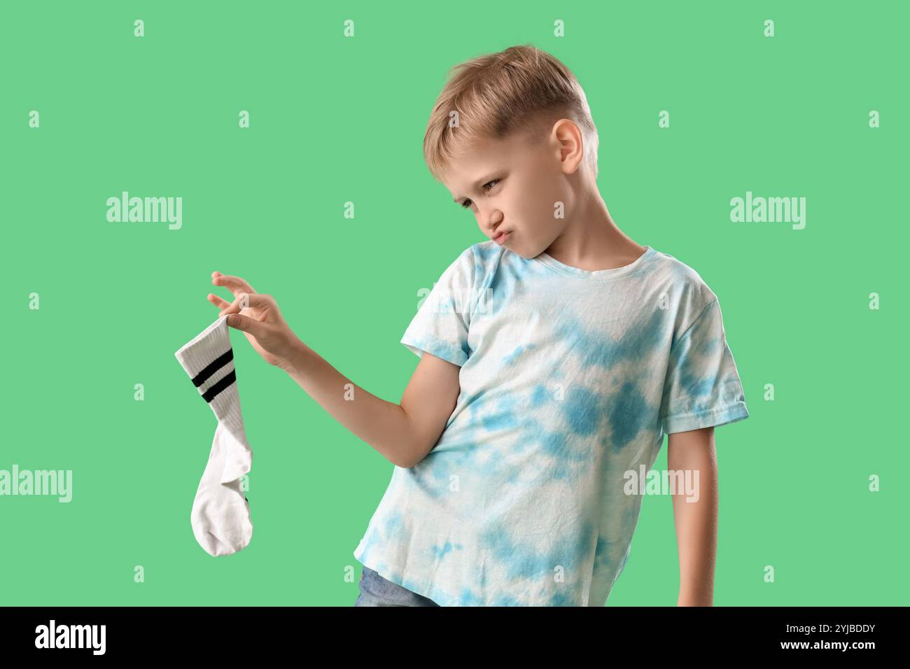 Disgusted little boy with dirty socks on green background Stock Photo ...