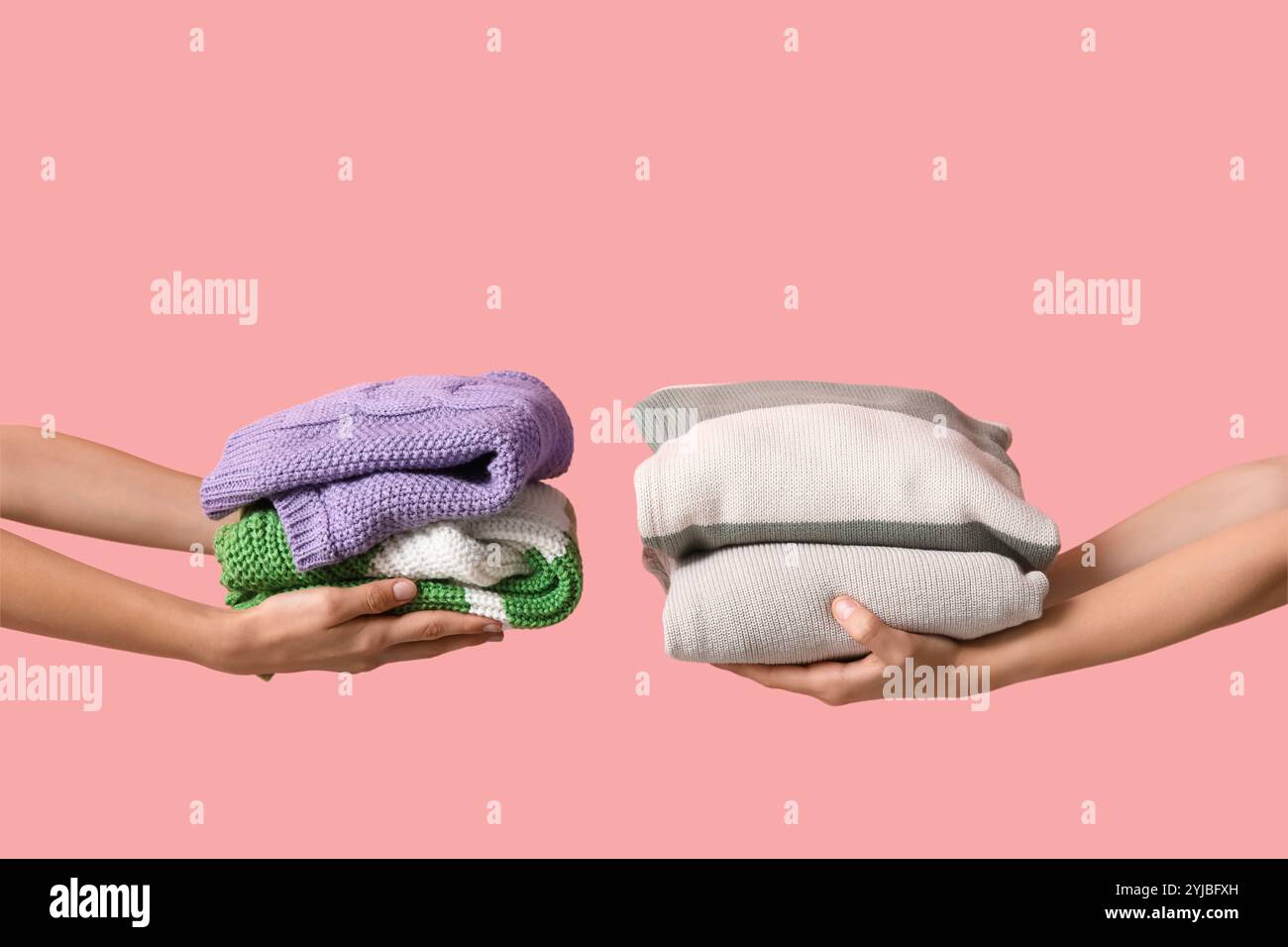 Female hands with stacks of different clothes on pink background Stock ...
