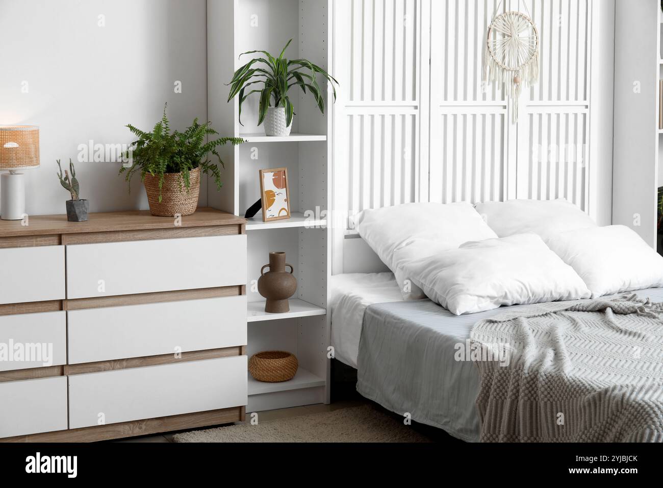 Cozy bed, shelving units and chest of drawers in interior of bedroom ...