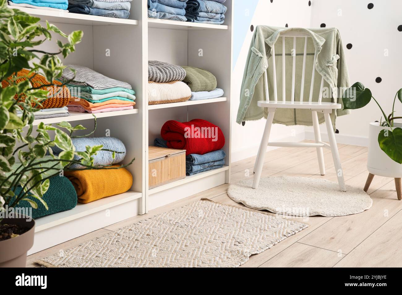 Shelving unit with clothes and chair in dressing room. Closeup Stock ...