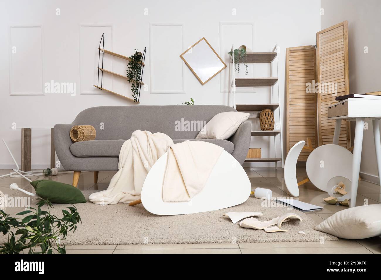 Interior of messy living room with sofa, overturned furniture and ...