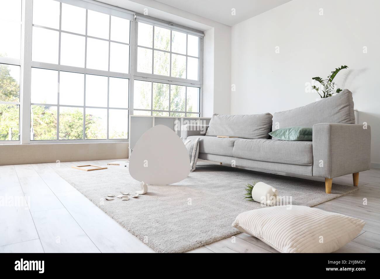 Interior of messy living room with sofa, overturned table and shelf ...