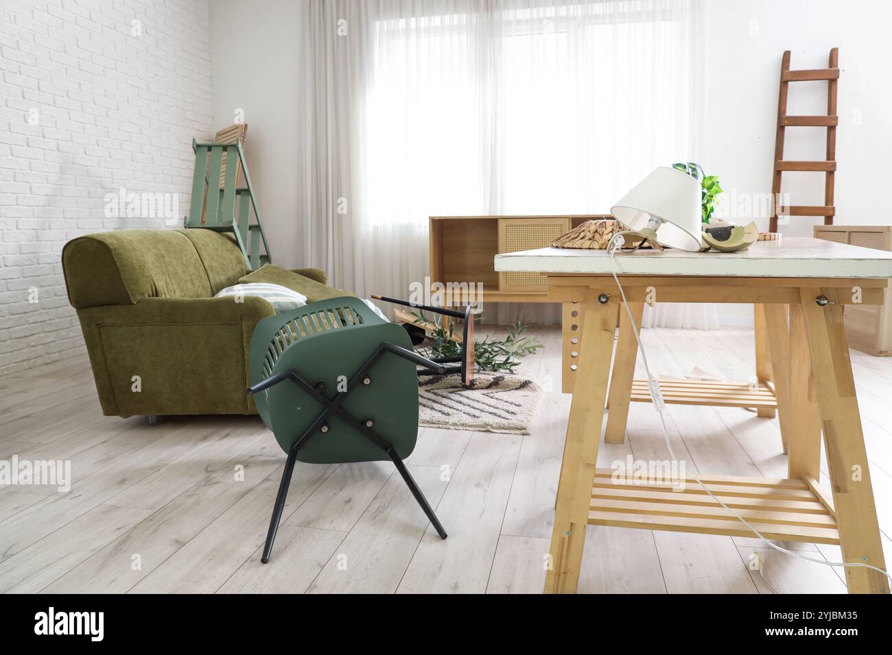 Interior of messy living room with sofa and overturned chair after ...