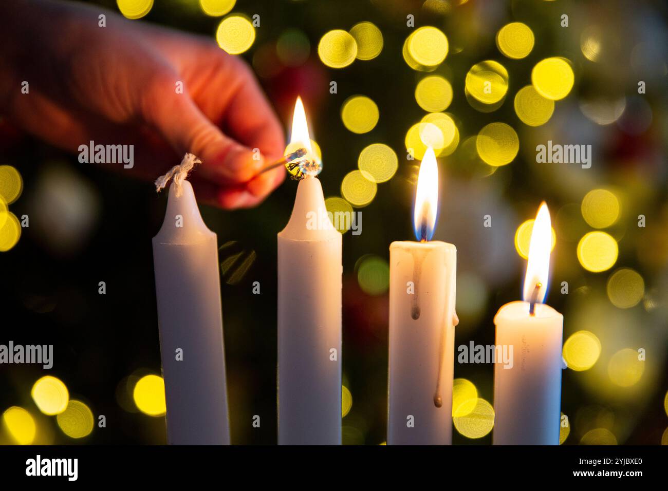 Hand lighting third candle with a match on Advent wreath with four ...