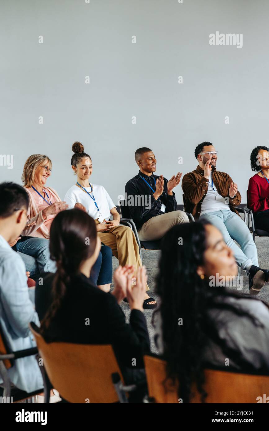 Corporate team engaging in an interactive workshop. A diverse group clapping during a meeting ...
