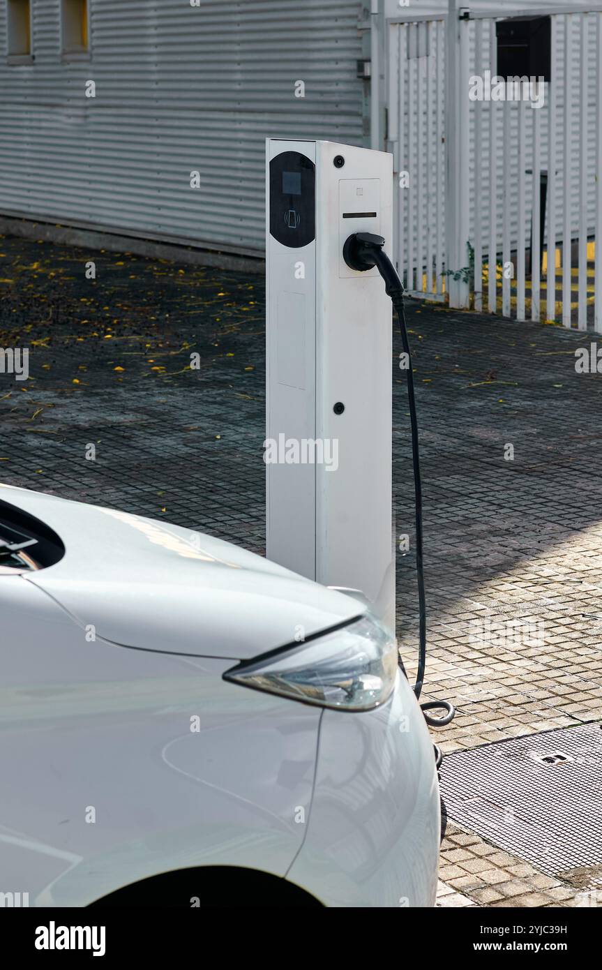 This image features an electric car at a charging station, showcasing ...