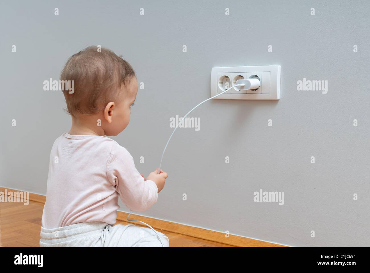 A young child curiously interacts with an electrical socket ... A young child curiously interacts with an electrical socket ...