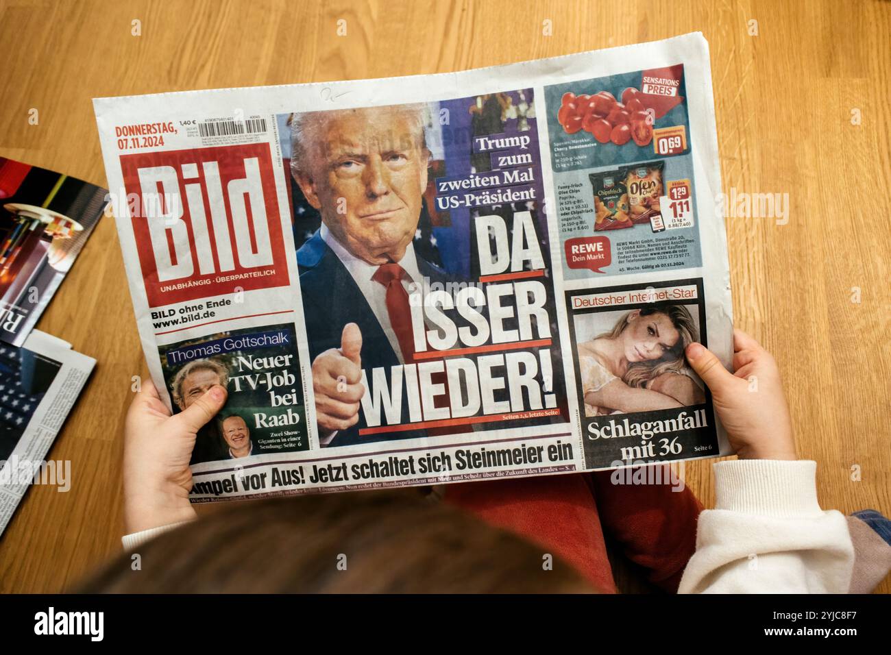 Paris, France - Nov 7, 2024: A toddler holds a German newspaper front ...