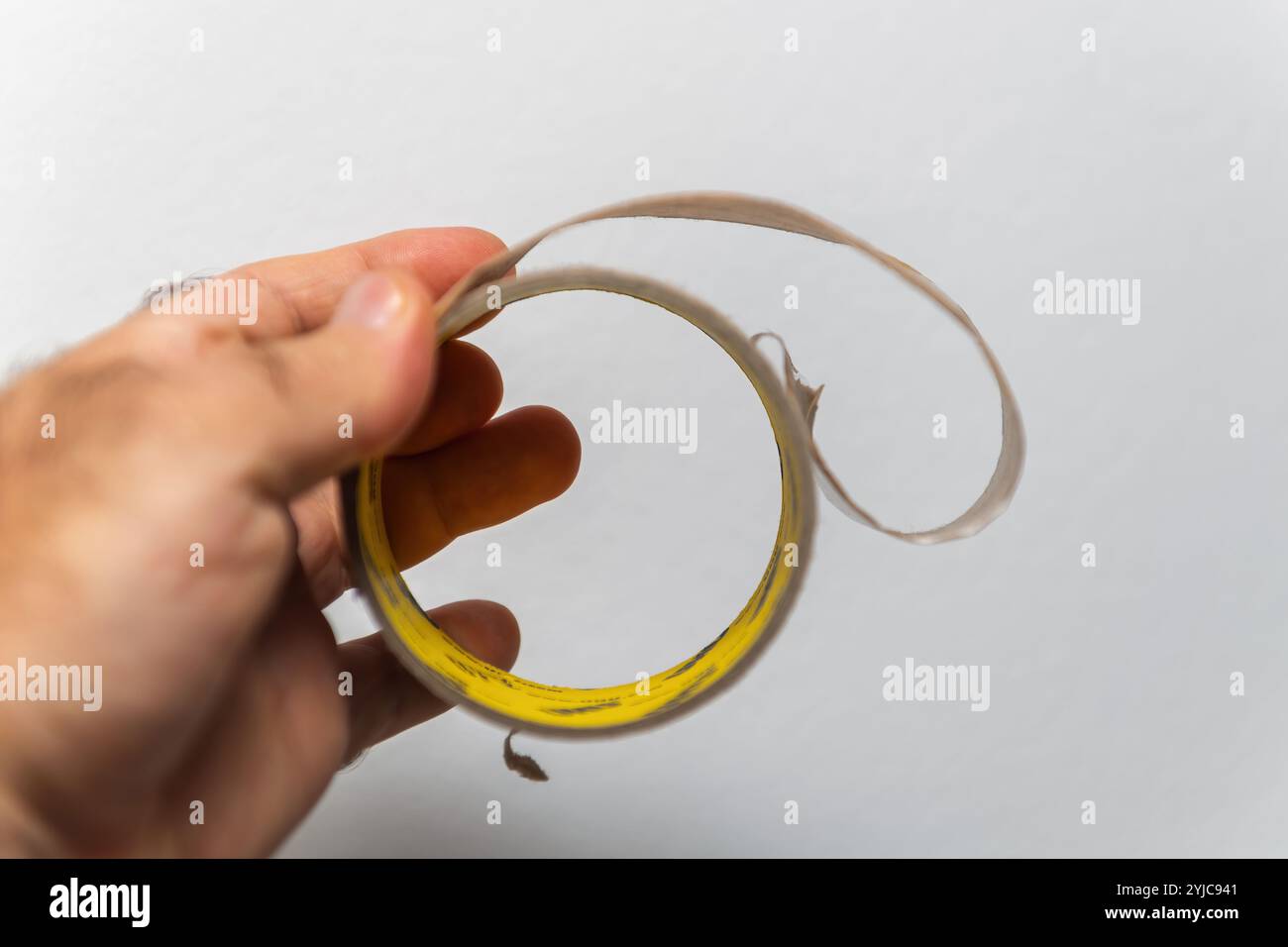 A side view of a hand holding an almost empty roll of Scotch tape, with ...