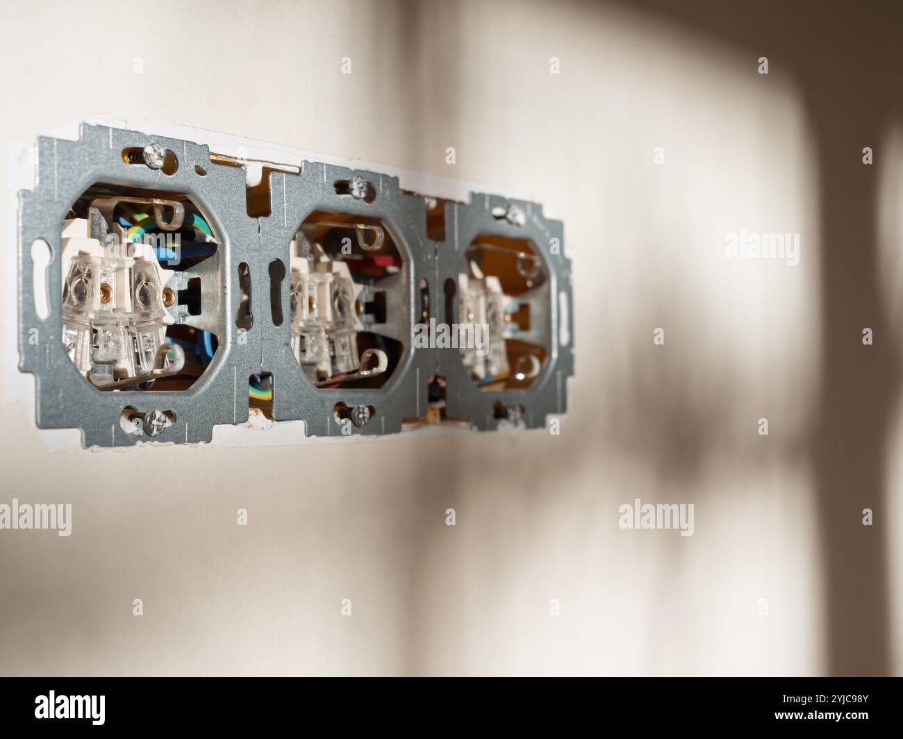 Three uninstalled wall socket frames with exposed wiring on a wall ...