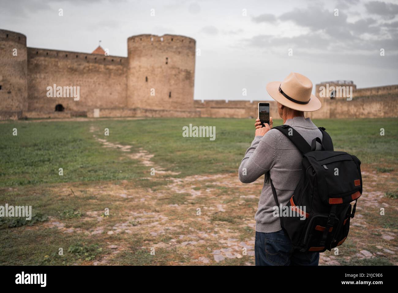 A retired male tourist takes photos while filming in an ancient ...