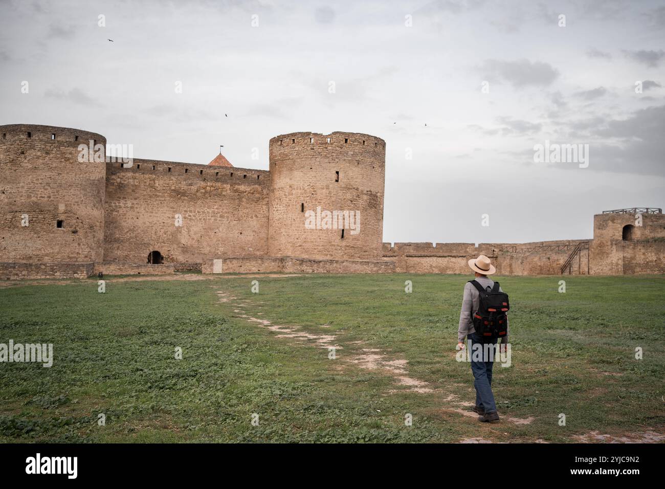 Rear view of a retired tourist walking towards an ancient fortress with ...