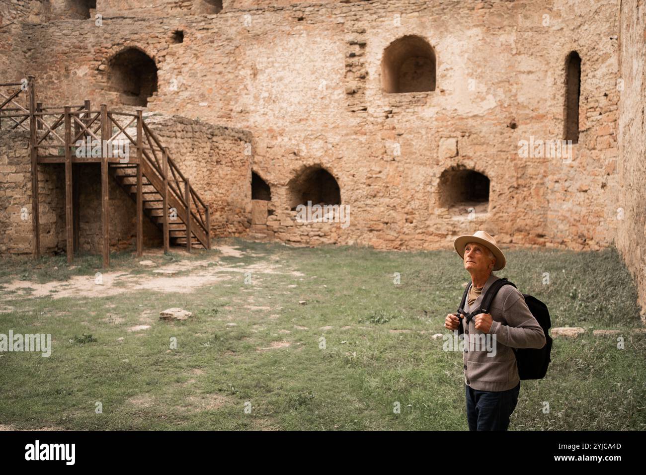 Elderly traveler admiring ancient fortress, discovering historic beauty ...