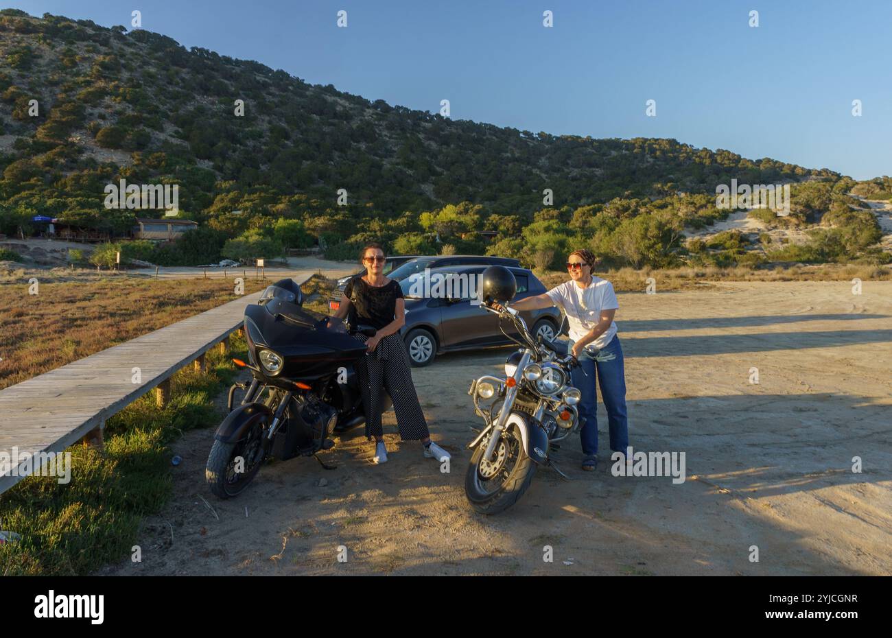 Two friends stand beside their motorcycles, soaking in the picturesque ...