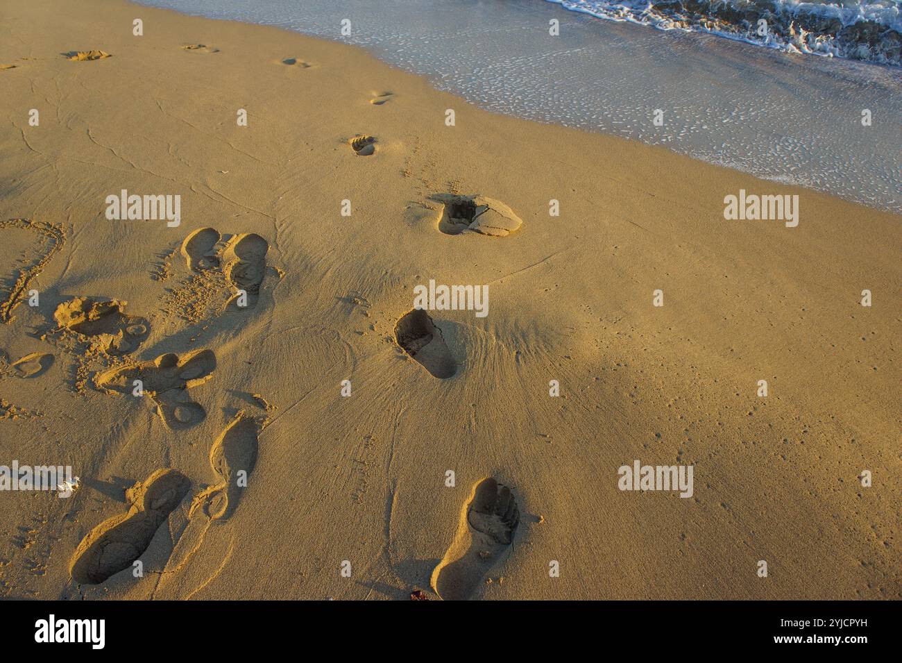 Gentle waves lap against the shore as footprints trace a tale of beach ...