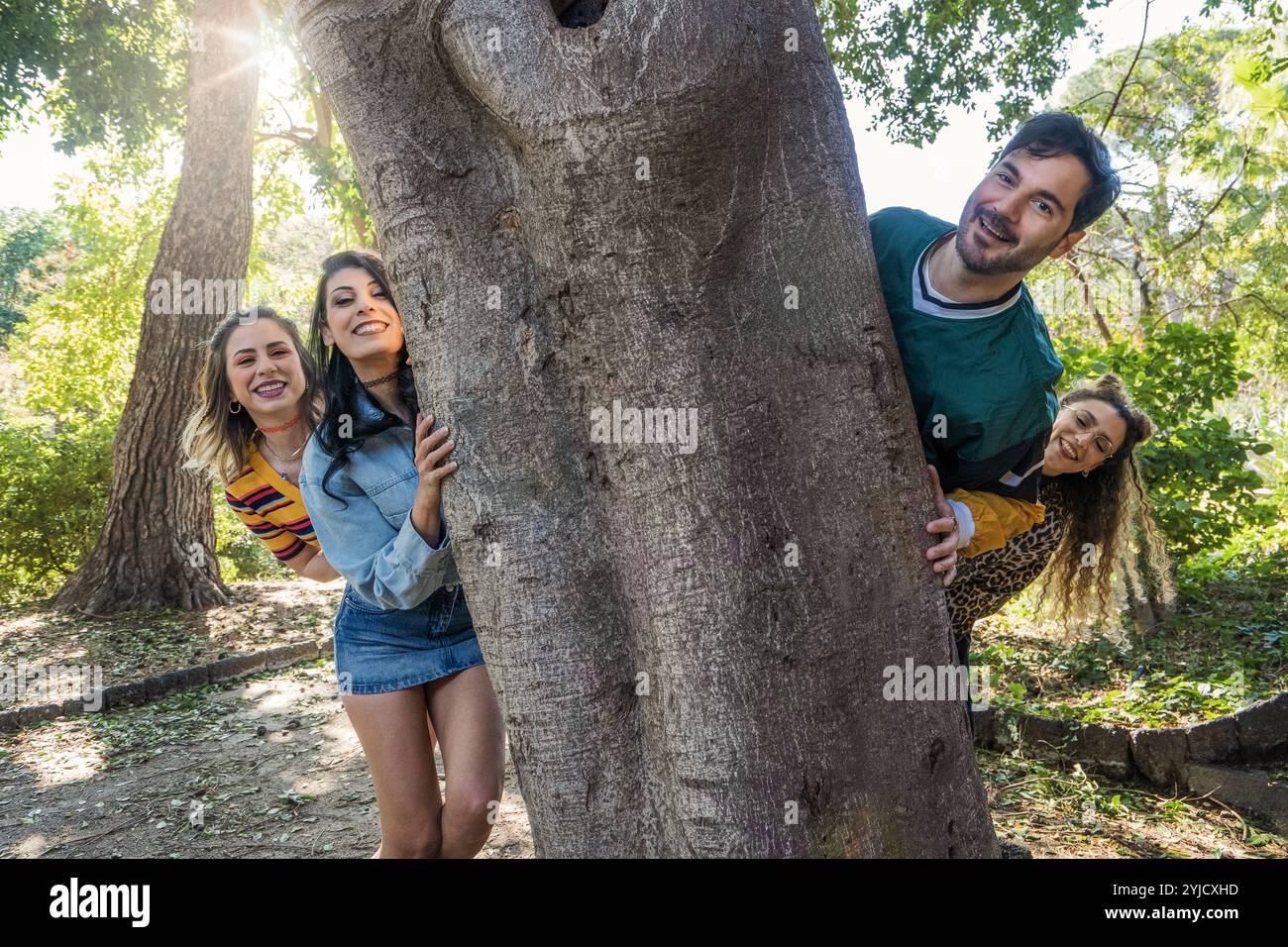Cheerful multiethnic group of friends having fun while hiding behind ...