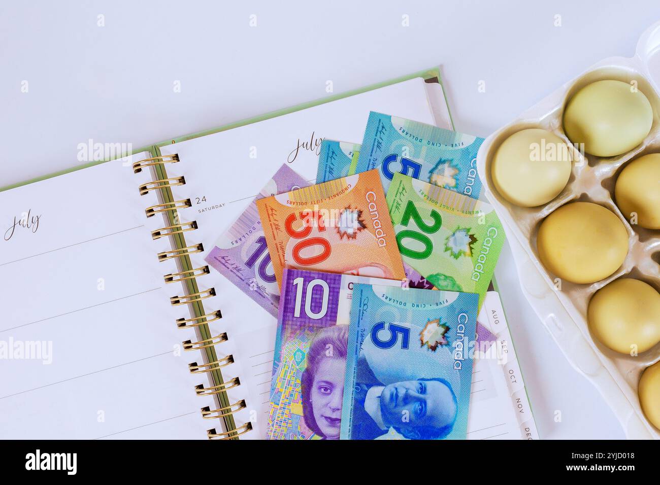Chicken eggs sit next to stack Canadian dollar cash bills, highlighting ...