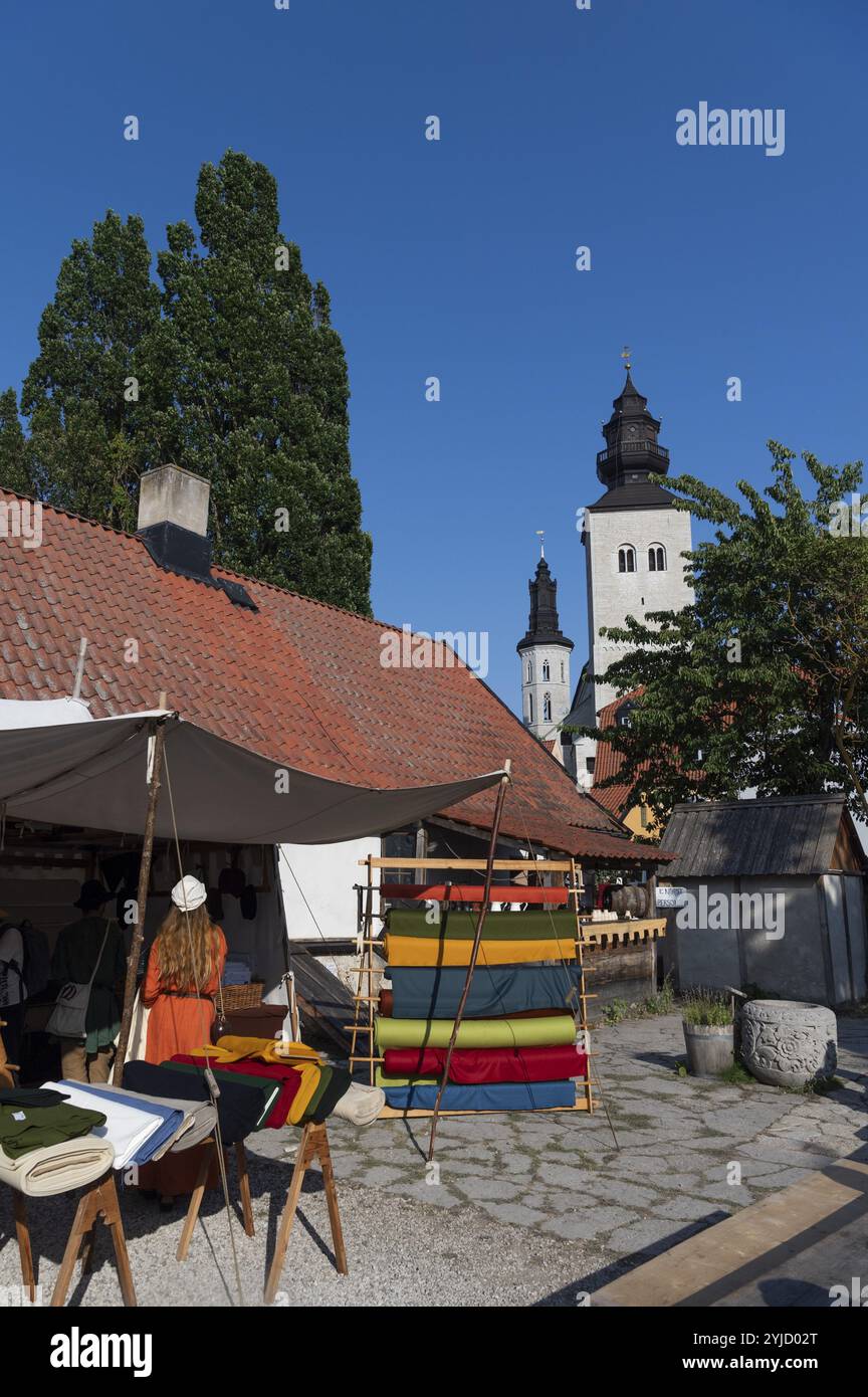 Stand with colourful bales of fabric and woman in medieval traditional ...