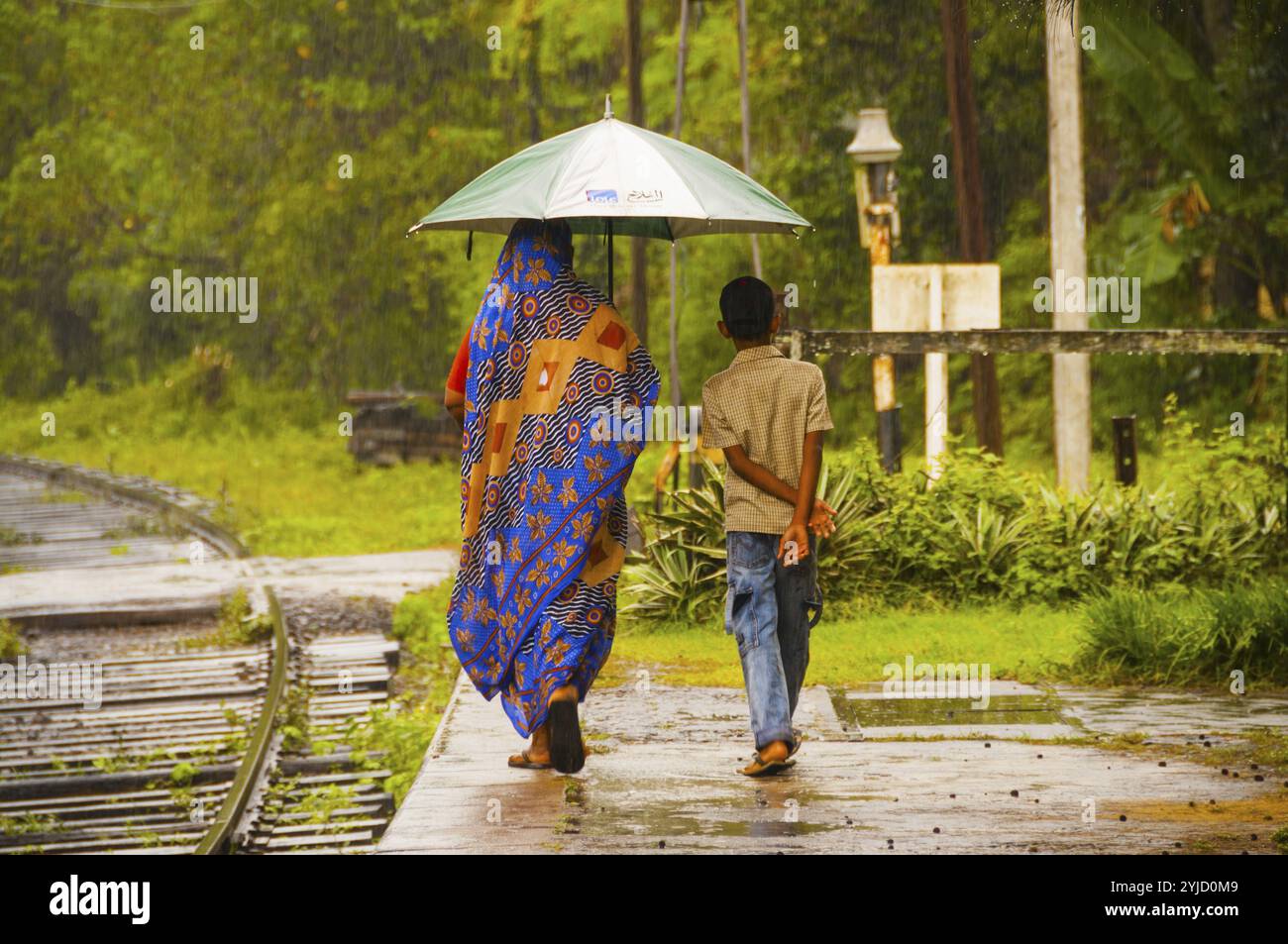 Sinhalese, mother and son, with umbrella in heavy rain, monsoon, railway station in Kalawewa ...