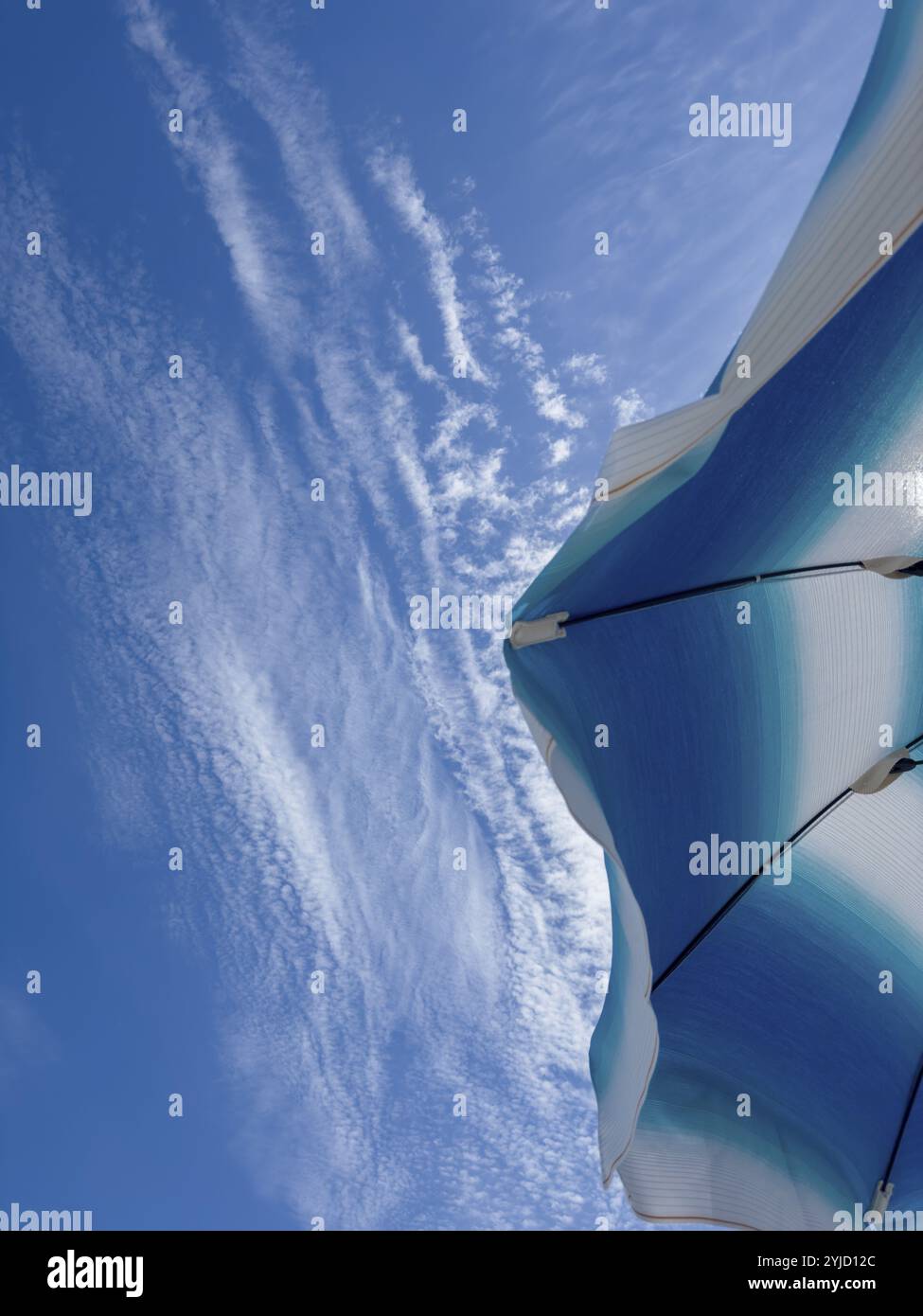 Parasol in front of a blue sky with clouds Stock Photo - Alamy