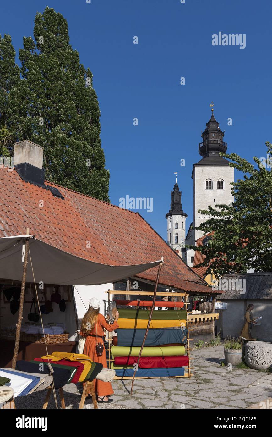 Stand with colourful bales of fabric and woman in medieval traditional ...