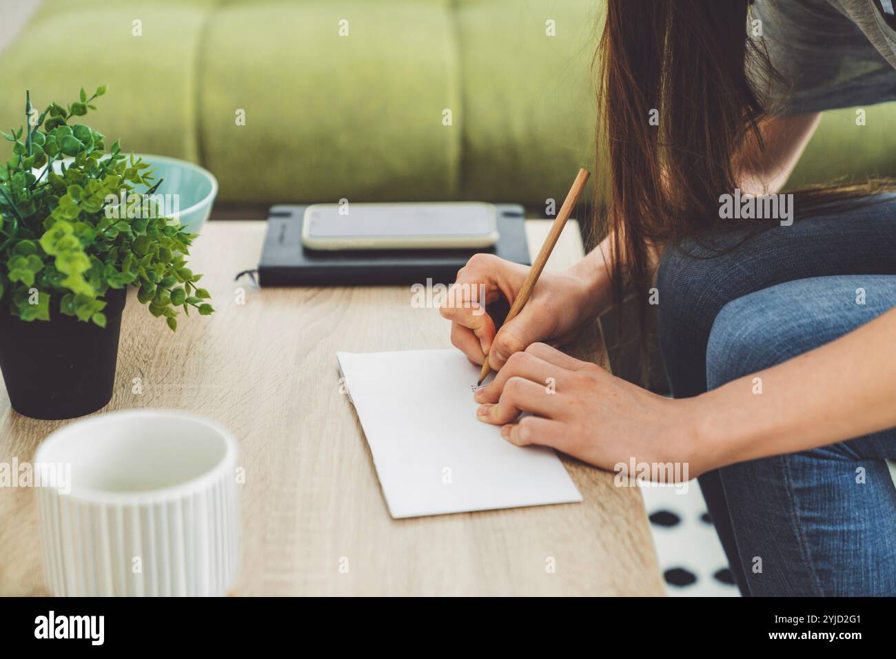Young caucasian woman with long brown hair in jeans working from home ...
