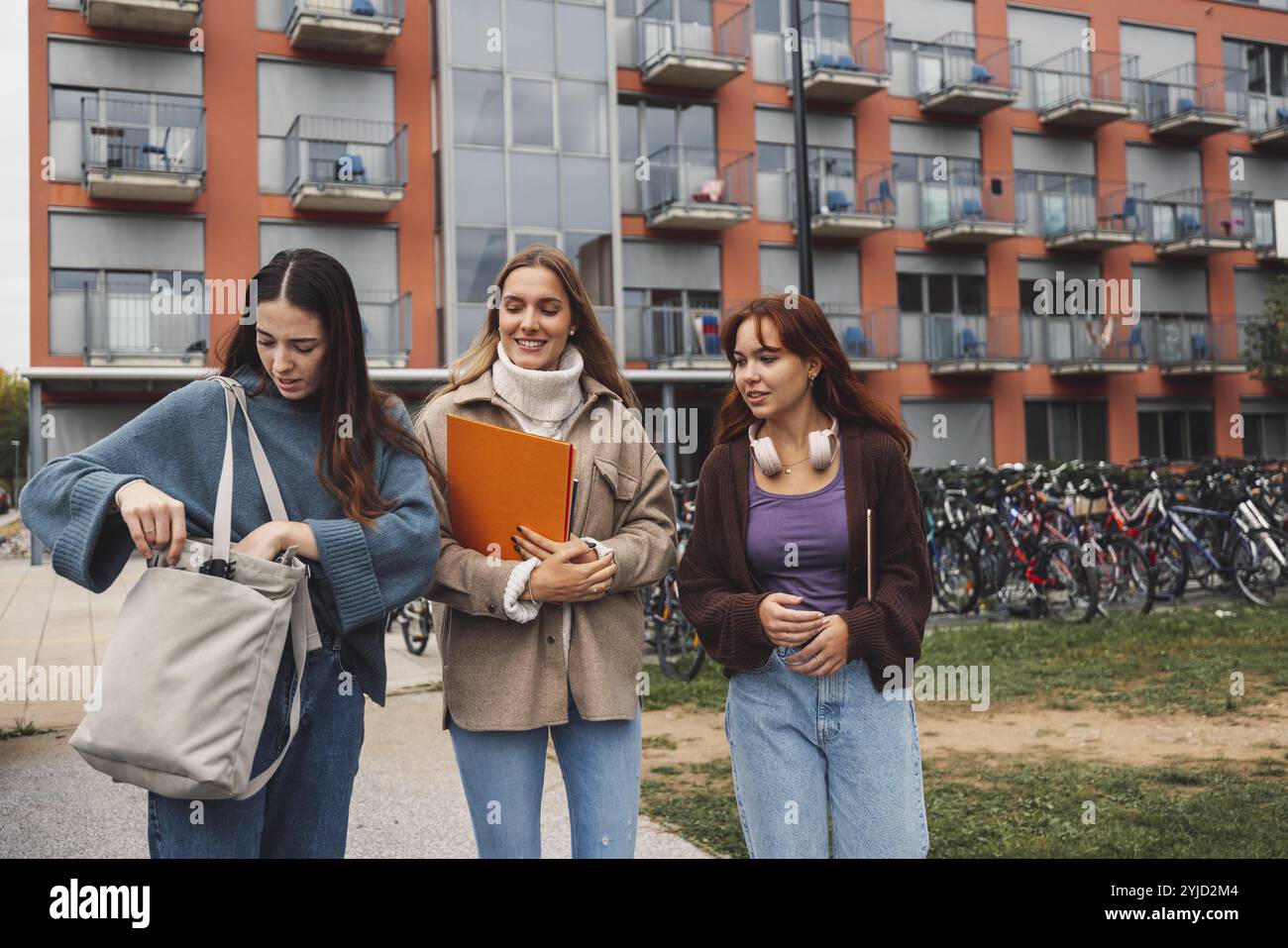 Group of three cheerful female collage students outside their dorm on a ...