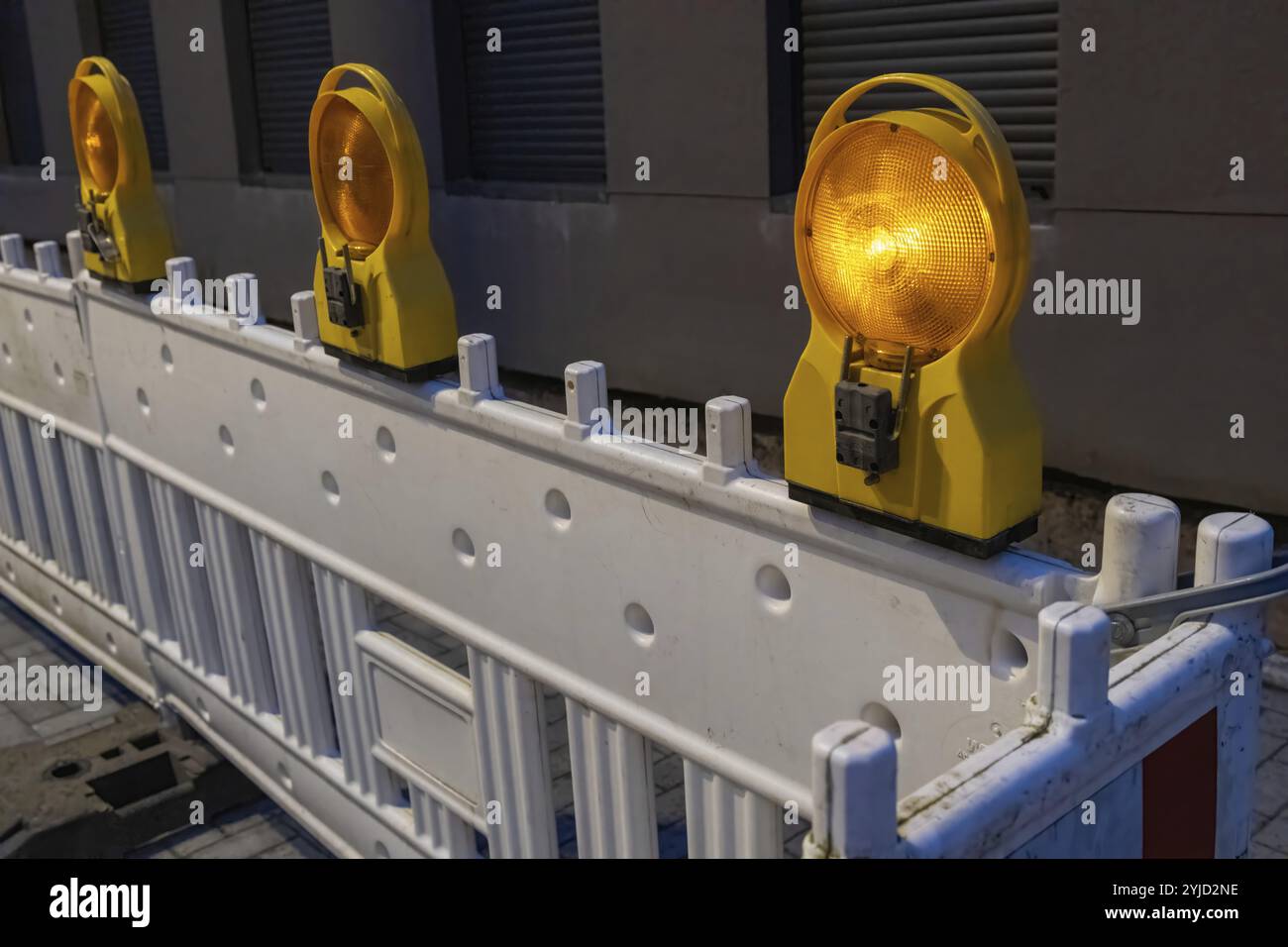 Flashing yellow rotating lights on white roadblock at night, protecting ...