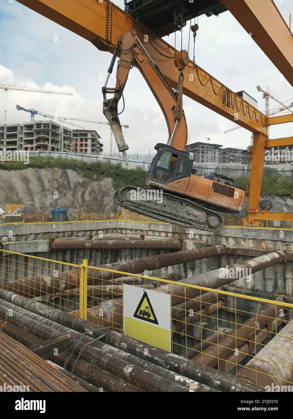 Crane lifting an excavator at a construction site with visible ...