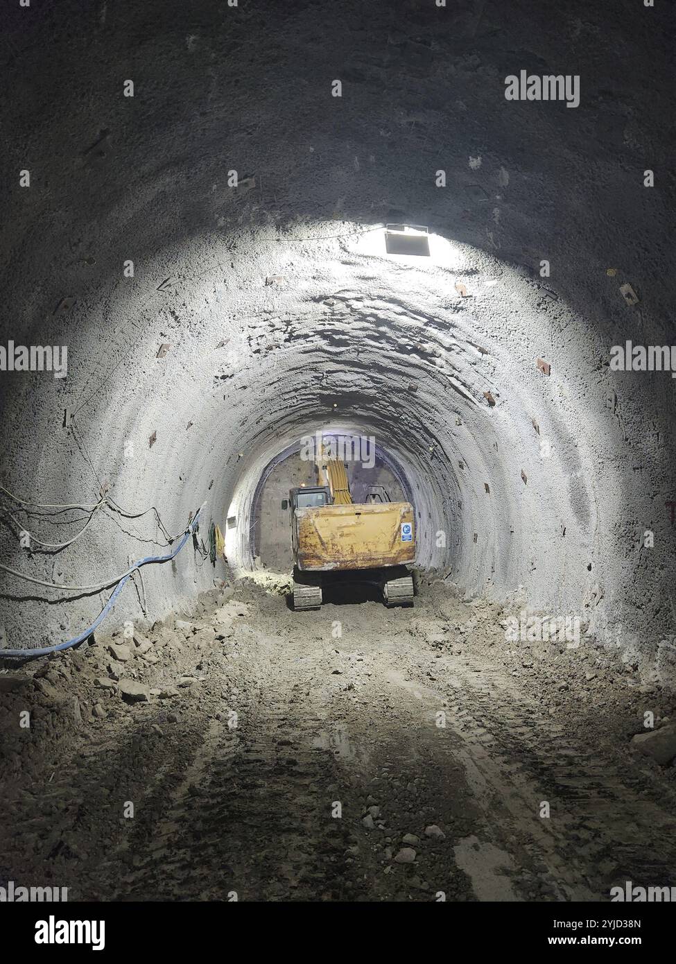 Excavator inside a dimly lit construction tunnel showcasing ongoing ...