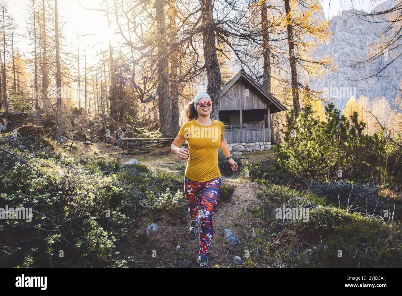 Joyful woman hiker running in the autumn forest, wearing an orange ...