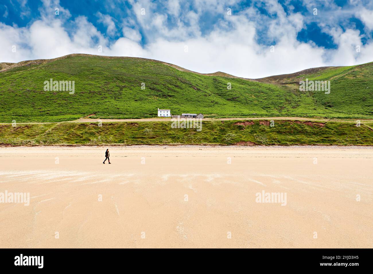 Woman walking along sandy beach - Rhossili Bay, Gower Way, Wales Stock ...