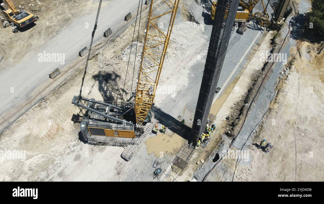 Crane lifting rebar with workers at a construction site viewed from ...