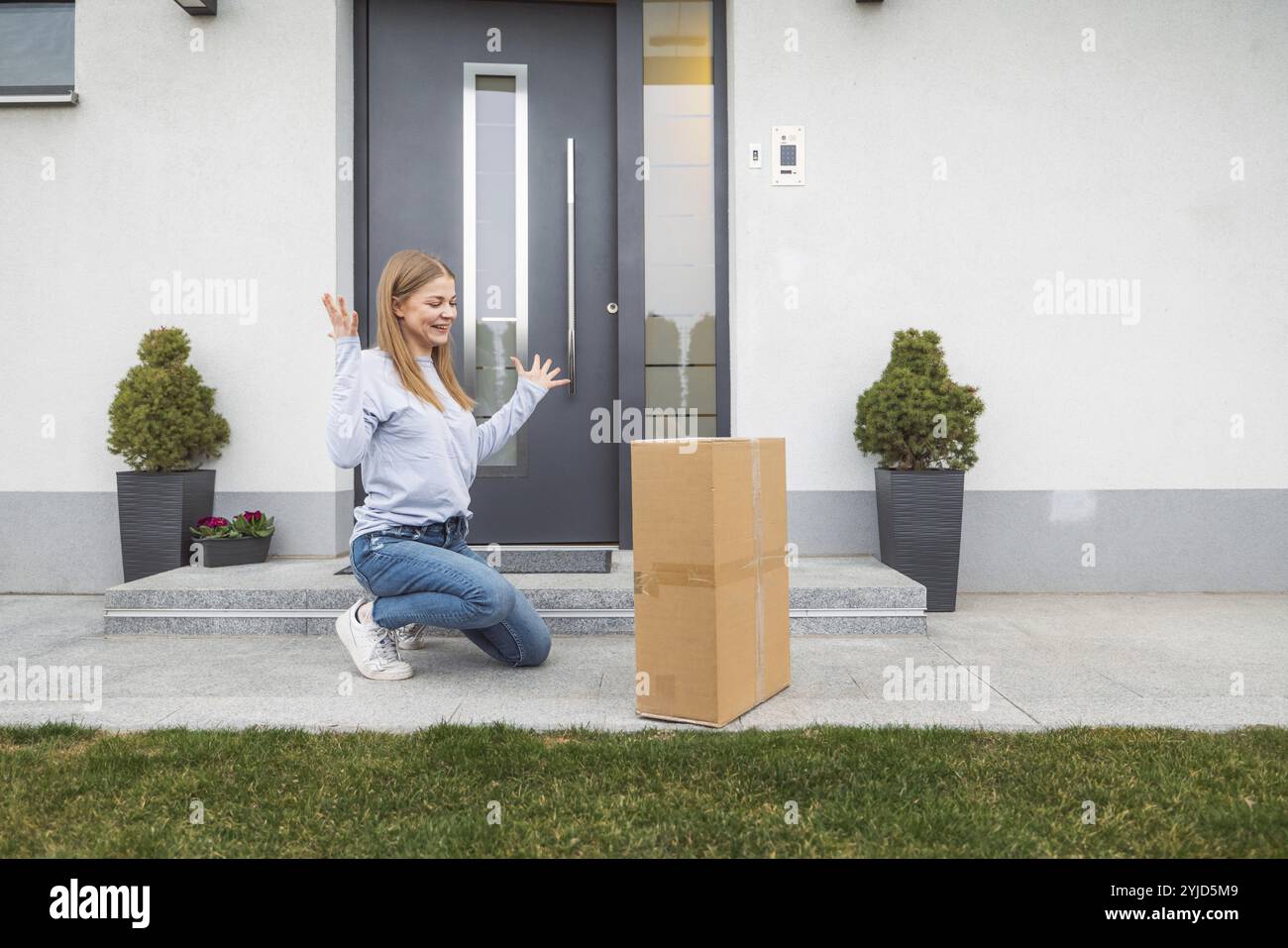 Thrilled caucasian woman kneeling down at the front door with a big ...