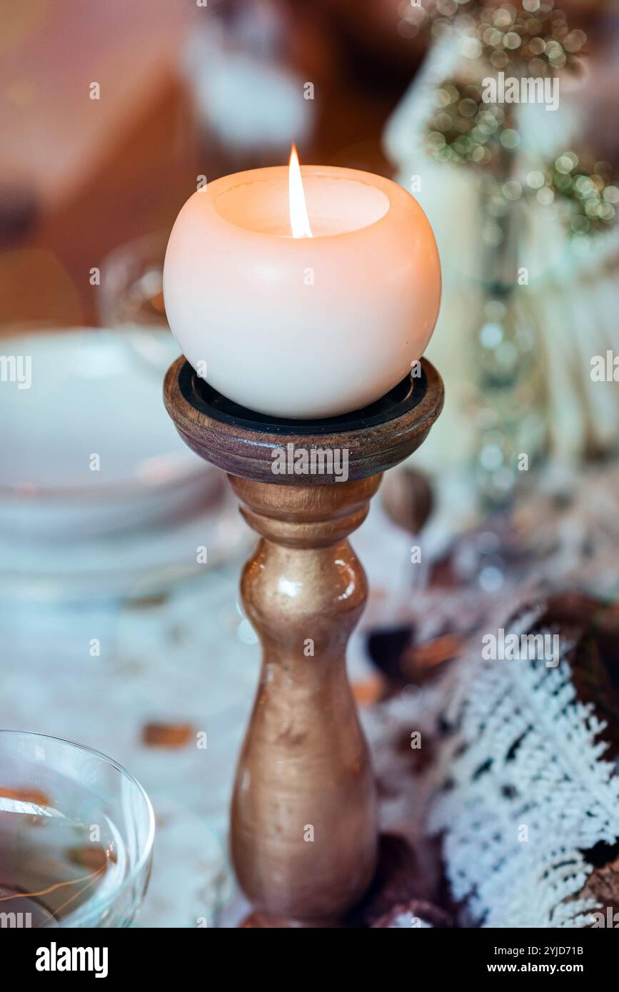 Round white candle burning on candlestick on set table for Christmas ...