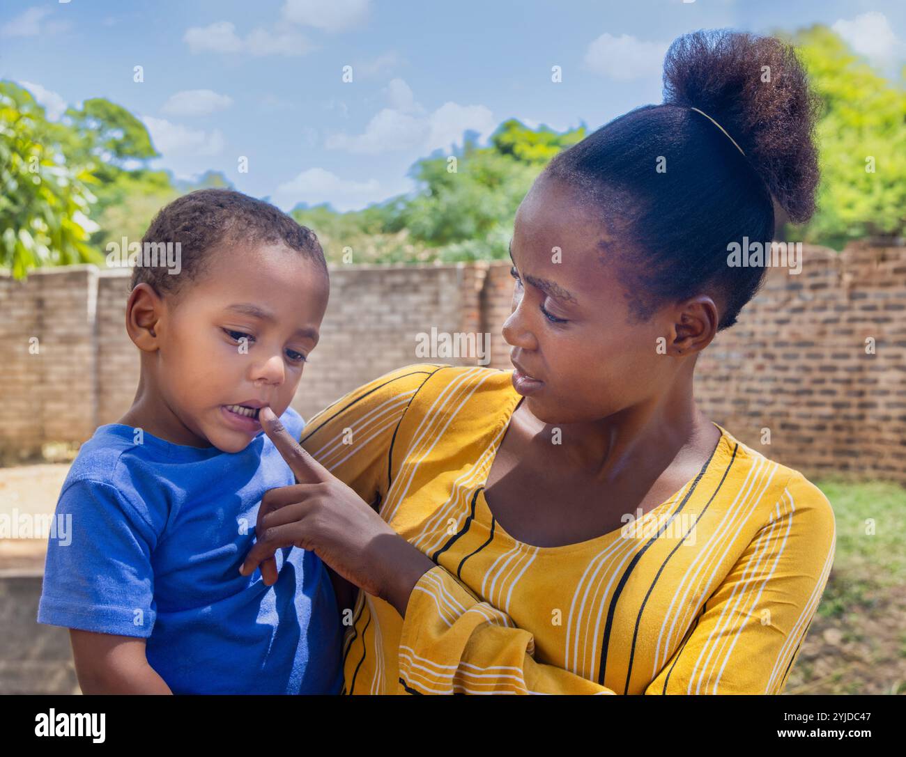 young african mother holding her crying child, trying to calm and ...