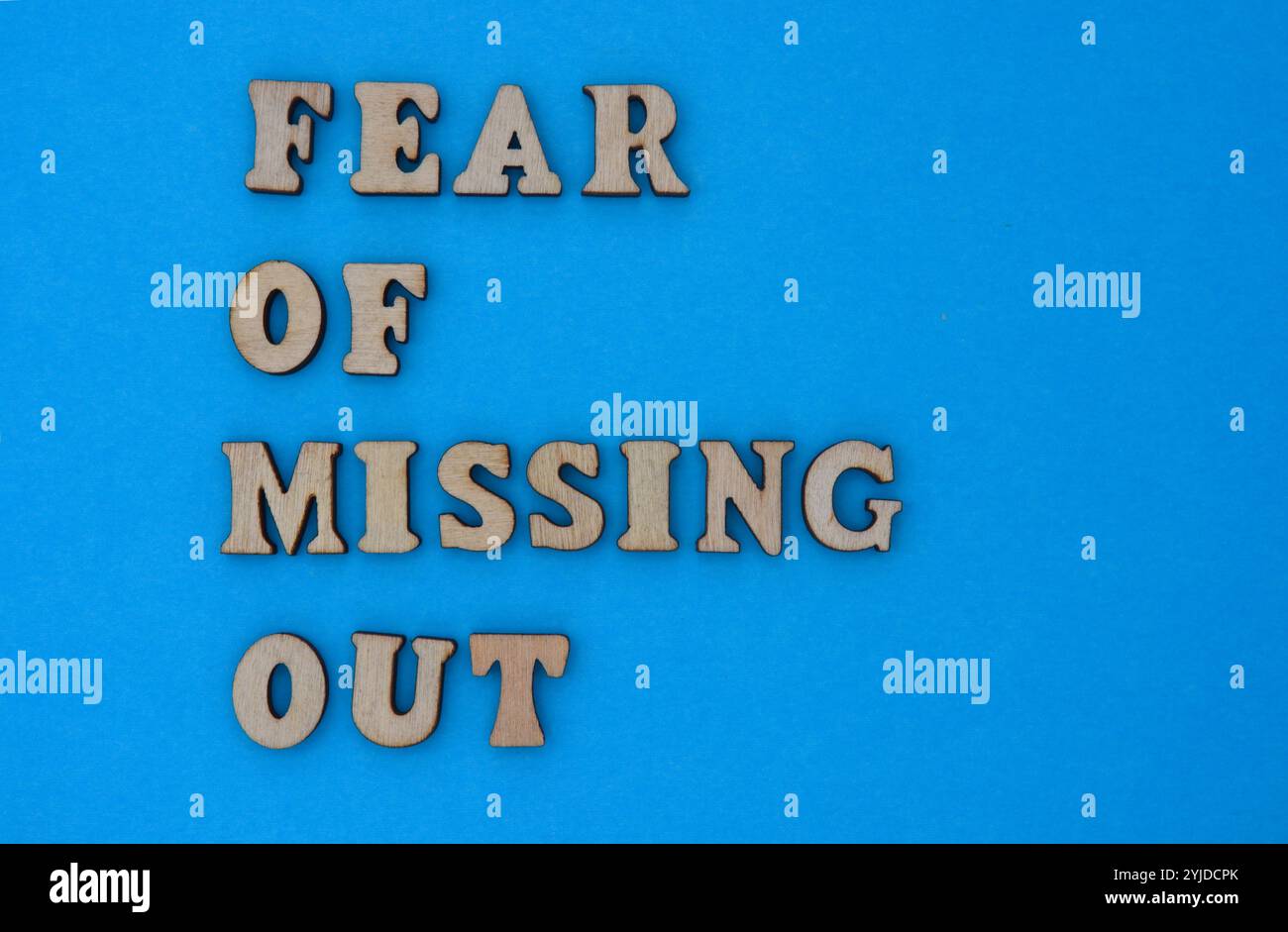 FOMO, abbreviation for Fear Of Missing Out, in wooden alphabet letters ...