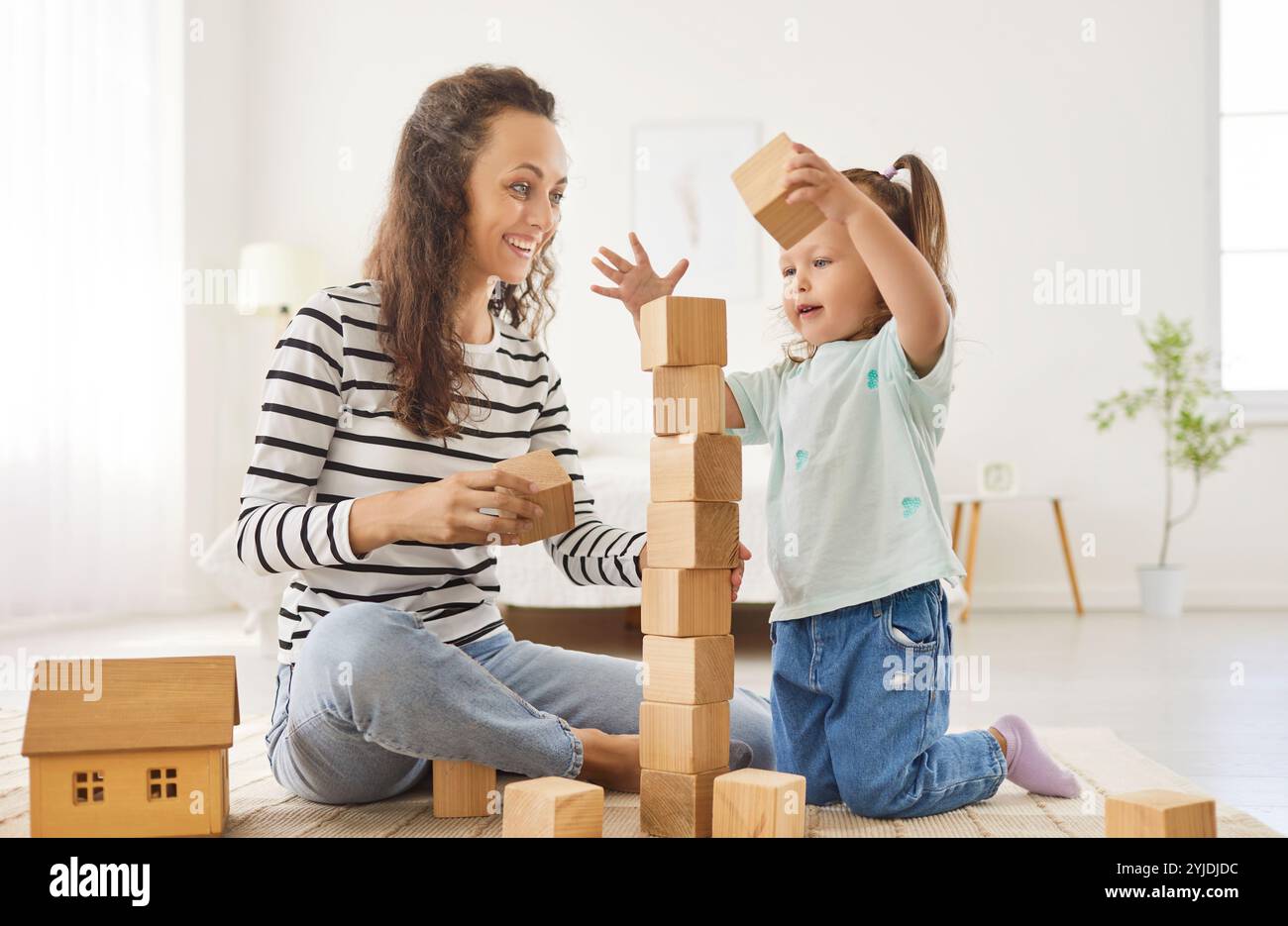 Happy playful smiling mother and baby daughter, babysitter nanny cube ...
