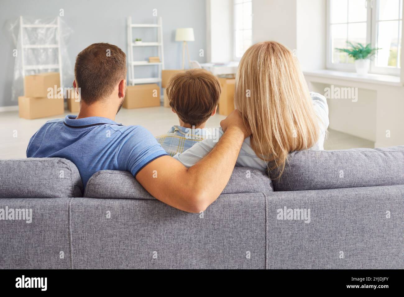 Loving close happy family sitting sofa rear view in new living room ...