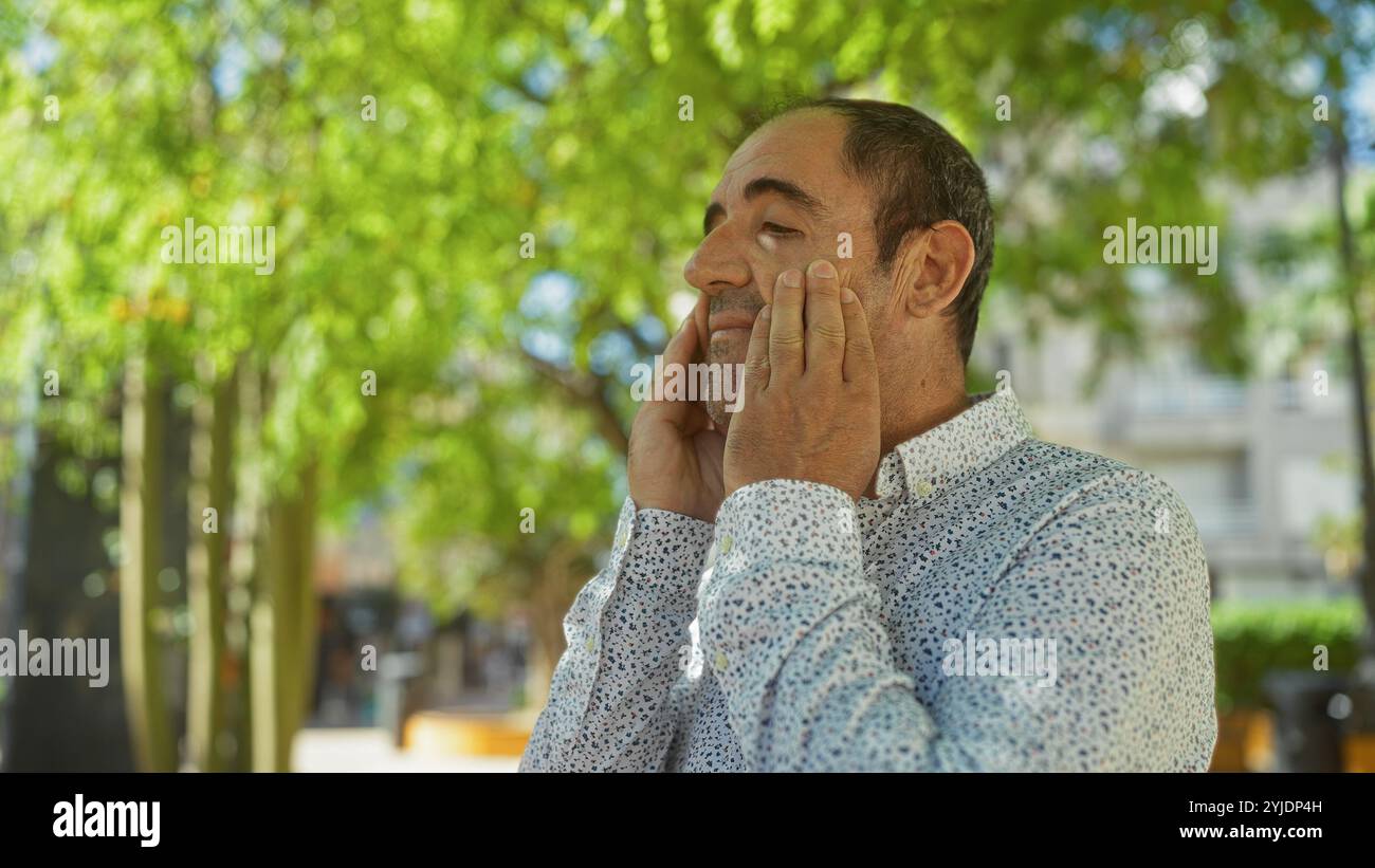 Tired hispanic man in an urban park, appearing exhausted and rubbing ...