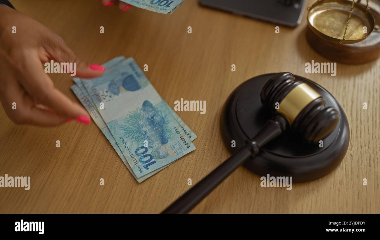 Woman's hand with pink nails counting brazilian reais on a wooden desk ...