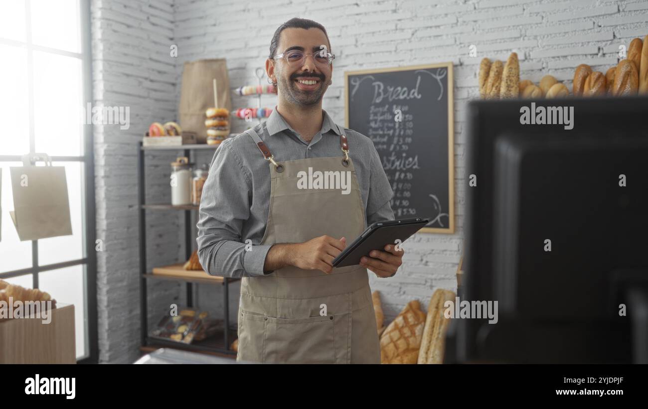Handsome man with moustache in bakery shop using tablet indoors with ...