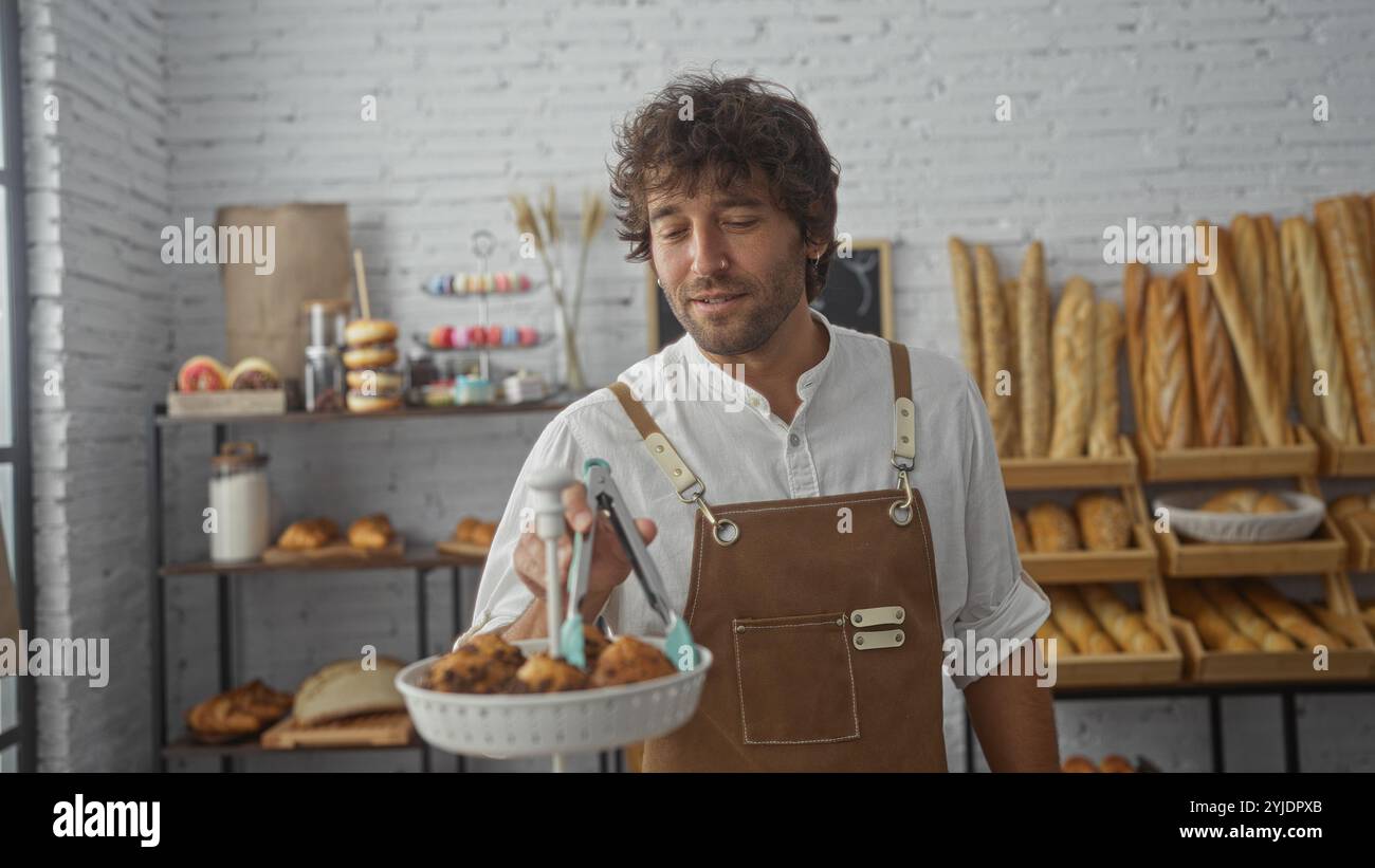 Young man in a bakery holding cookies with tongs while surrounded by ...