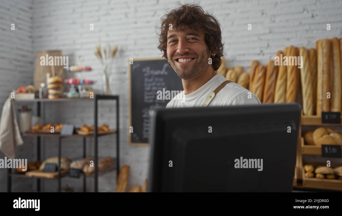 Young man smiling at the camera in a bakery shop interior with fresh ...