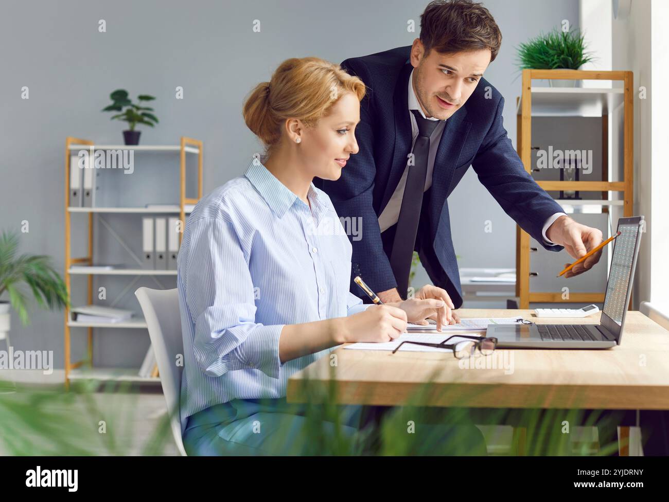 Two company employees working together, looking through accounting data ...