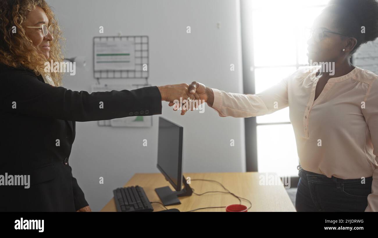 Women colleagues greeting each other with a fist bump in an office ...
