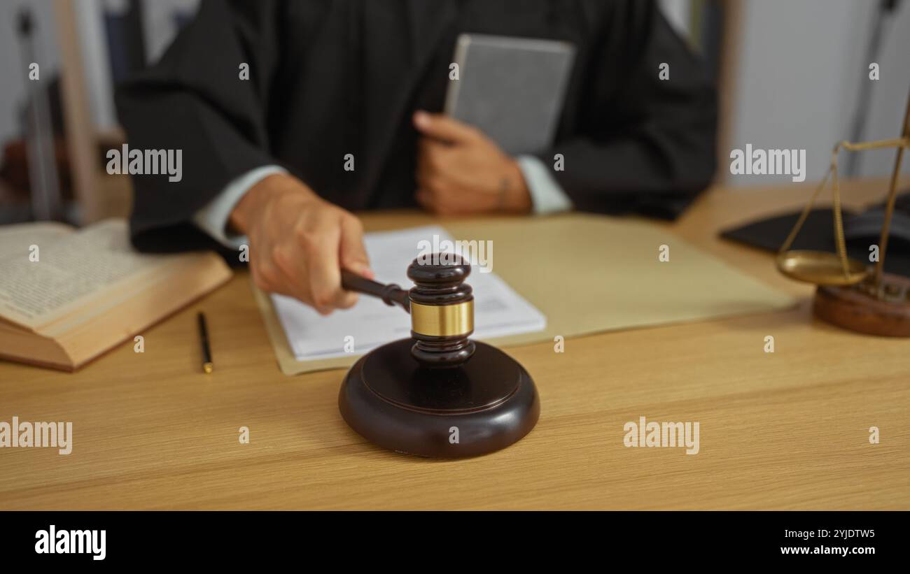 Judge striking gavel in courtroom with book pen and scale of justice on ...